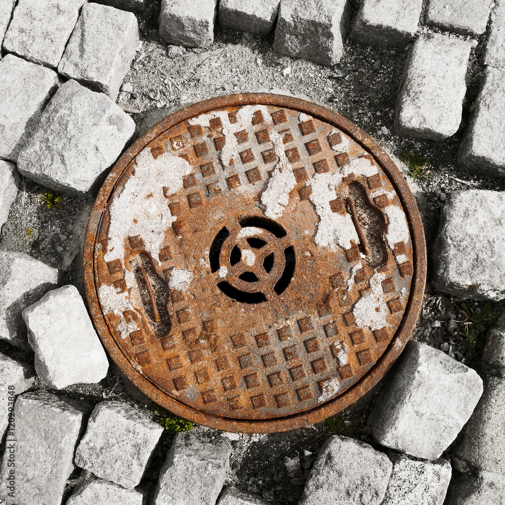 Old rusty manhole cover on the road from a stone blocks Stock Photo ...