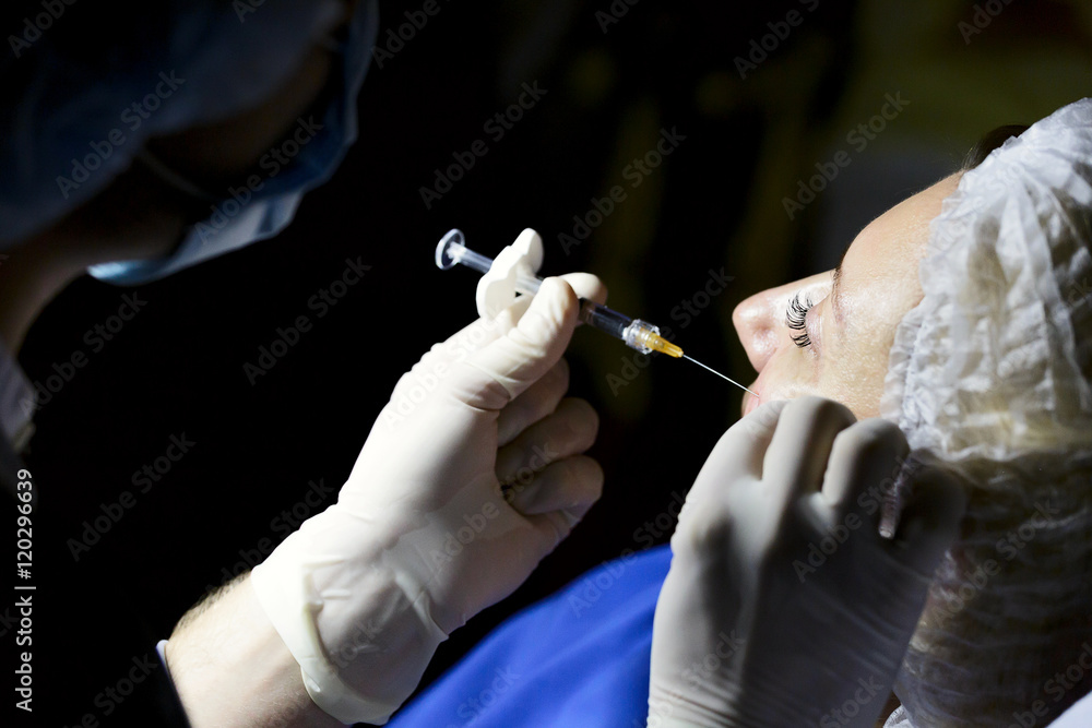 Doctor cosmetologist doing botox injection syringe. The doctor does an ...