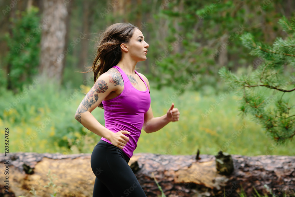 Woman running in wooded forest area, training and exercising for trail ...
