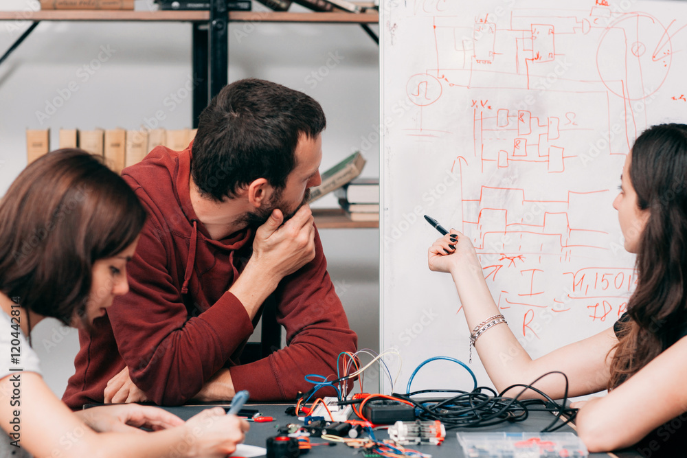 Wiring diagram discussing at laboratory. Young engineers creating new ...