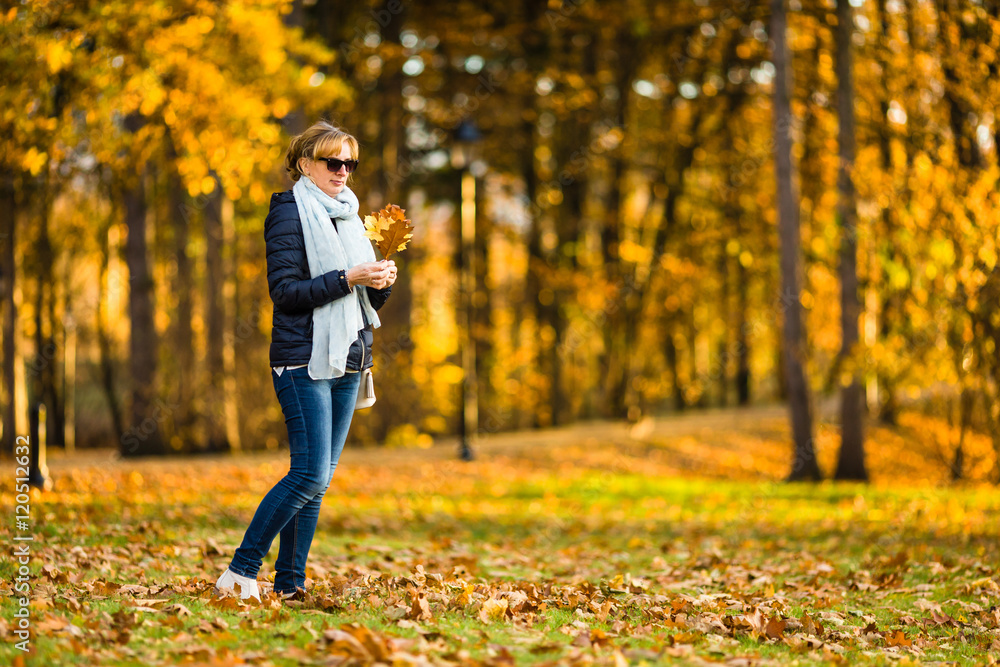 Middle-aged woman walking in city park Stock Photo | Adobe Stock