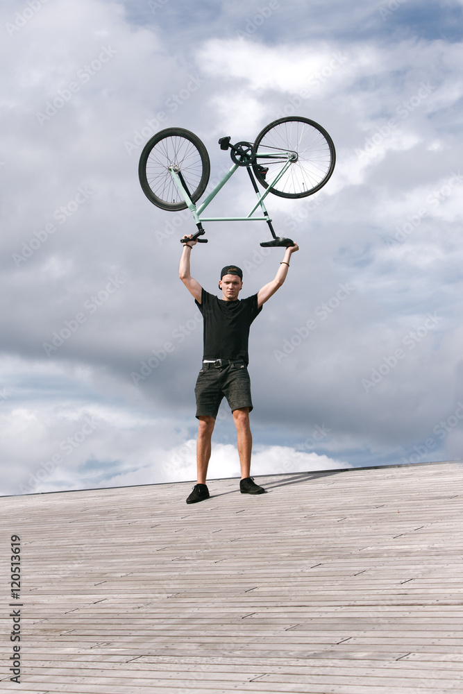 Serious boy with bike in arms above the head Stock-Foto | Adobe Stock