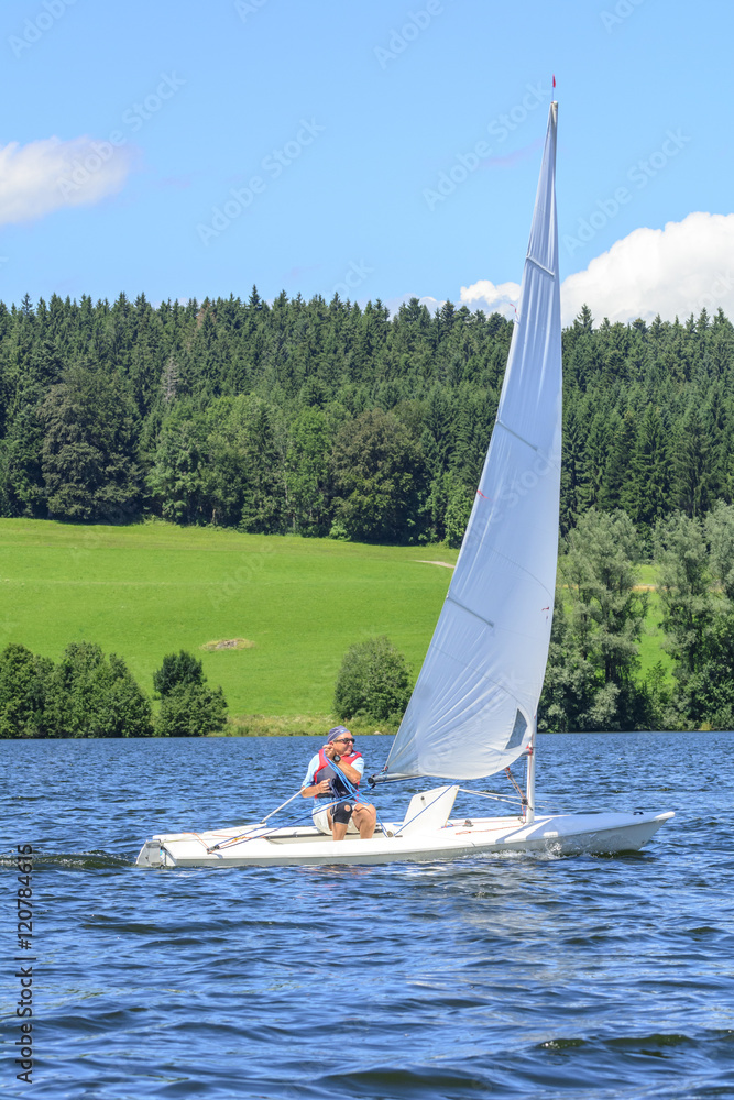 Mann segelt mit einer Jolle auf einem See Stock Photo | Adobe Stock