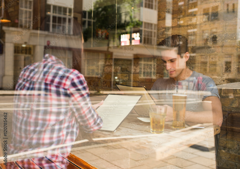 Window view of young couple reading menus in restaurant Stock Photo ...