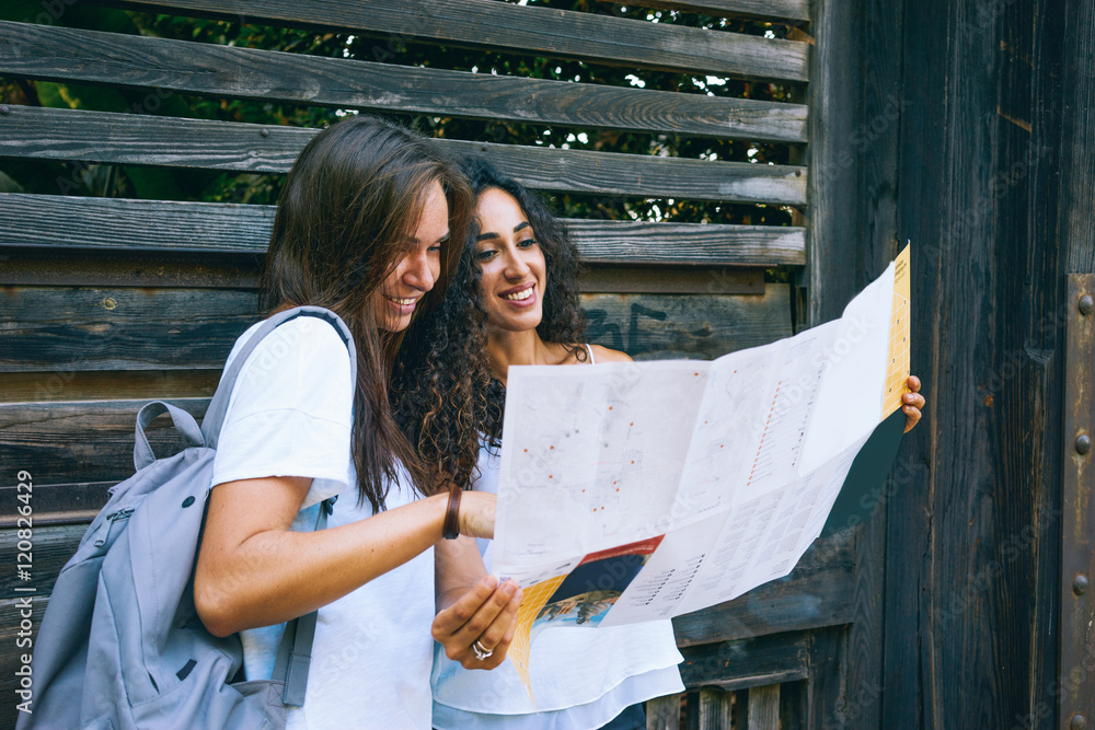 Two young cute girls are exploring a paper map to find all the ...