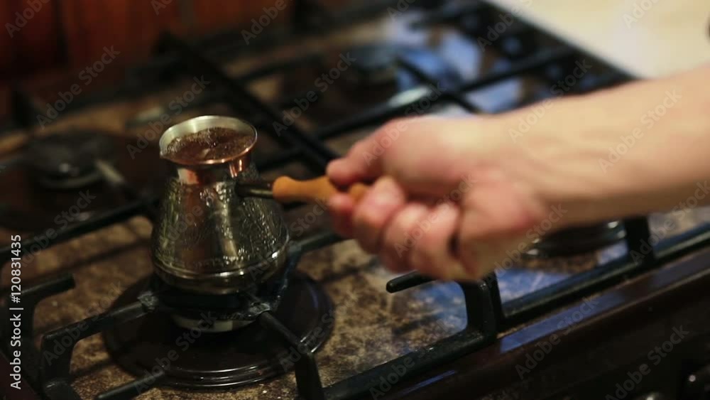 Coffee boiling in a coffee pot. Hands of a man taking the pot and ...