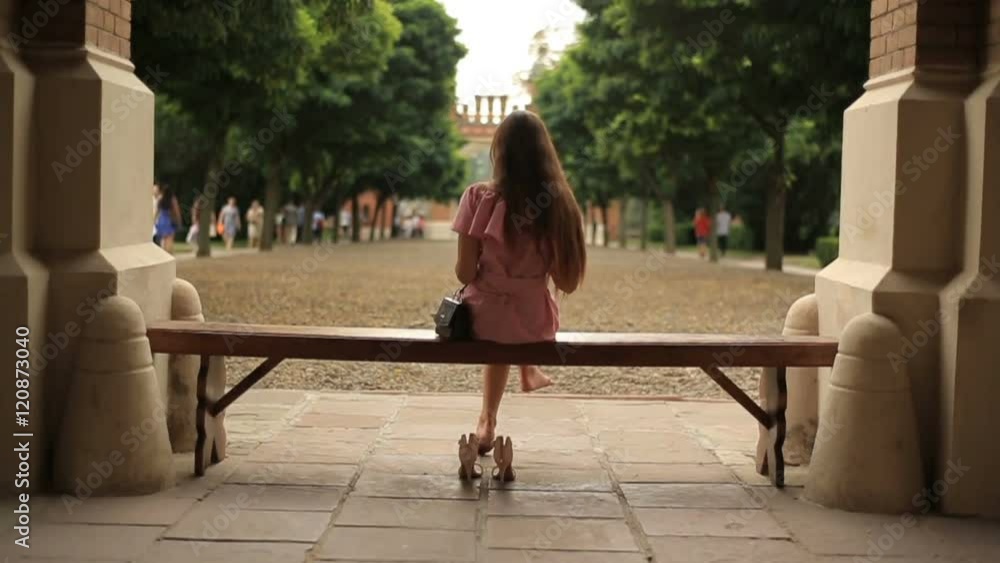 Teenage girl sitting down on bench in nature and reading a book ...
