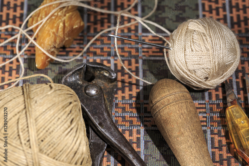 Leather needle beside waxed thread and hand tools used by shoemakers ...