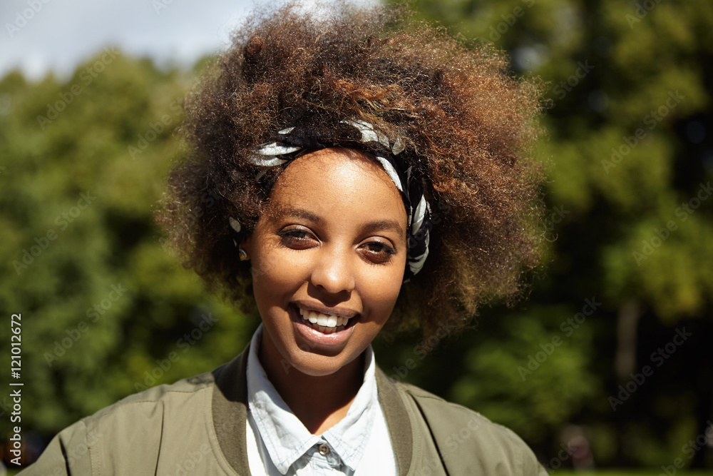 Outdoor shot of beautiful dark-skinned woman with curly hair and ...