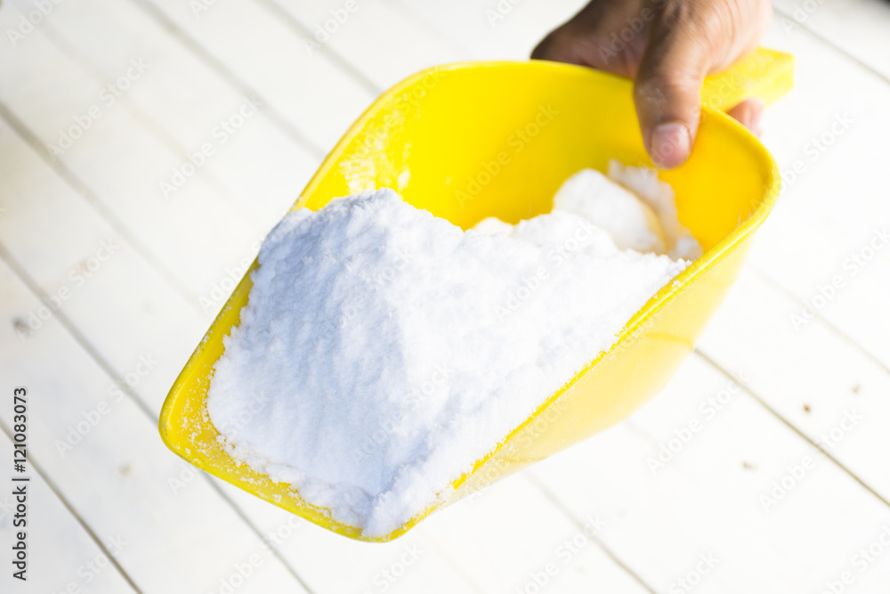 Dextrose in yellow shovel in hand on wooden white table Stock Photo ...