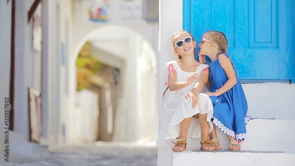 Cute little girls at street of typical greek traditional village with ...