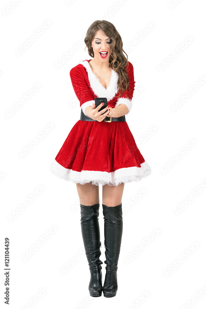 Excited cheerful female Santa Claus typing message on smart phone touch ...