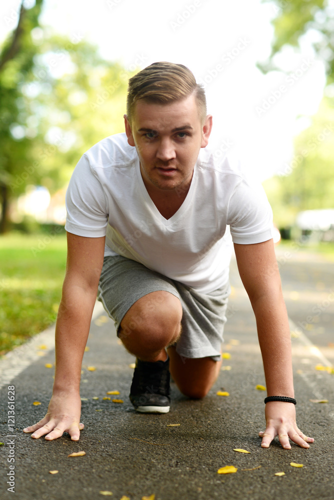 Blond man getting ready to run on a running track Stock Photo | Adobe Stock
