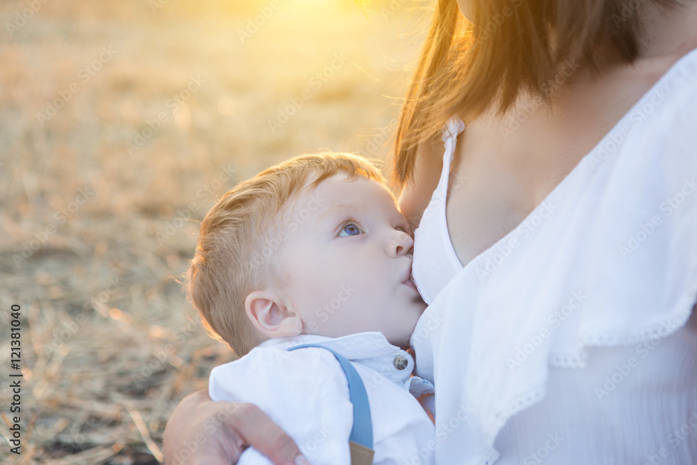 Beautiful happy mother breastfeeding her baby boy outdoor. Mother ...