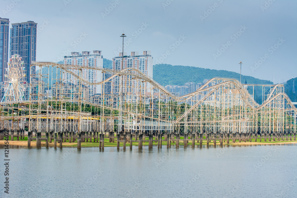 Roller coaster steel structure built above a lake with background of ...