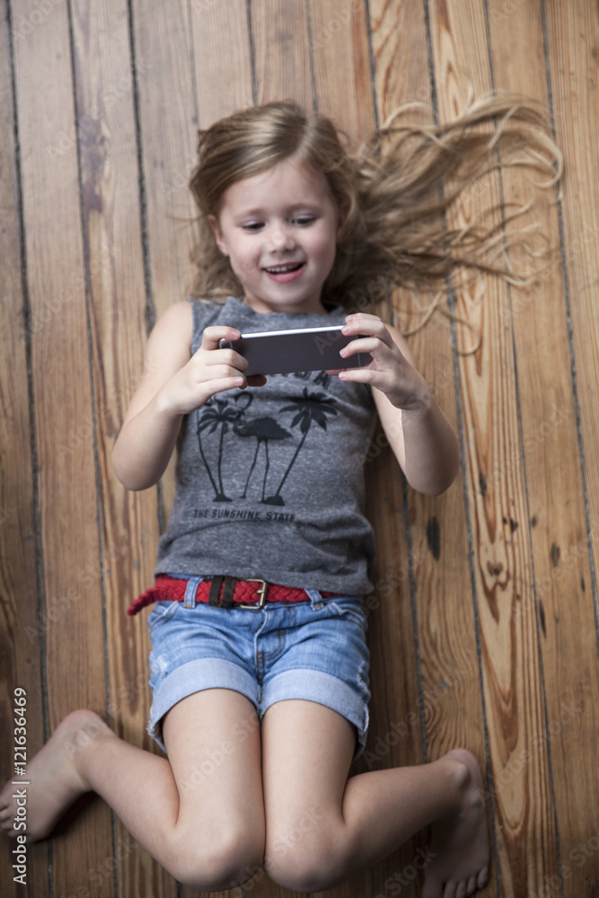 Little girl lying on floor using smartphone Stock Photo | Adobe Stock