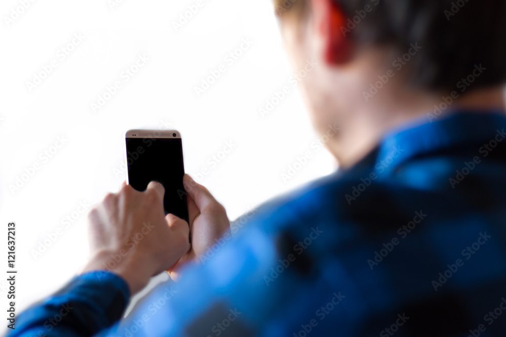 Junger Mann mit kariertem Hemd und Smartphone in der Hand, freigestellt ...