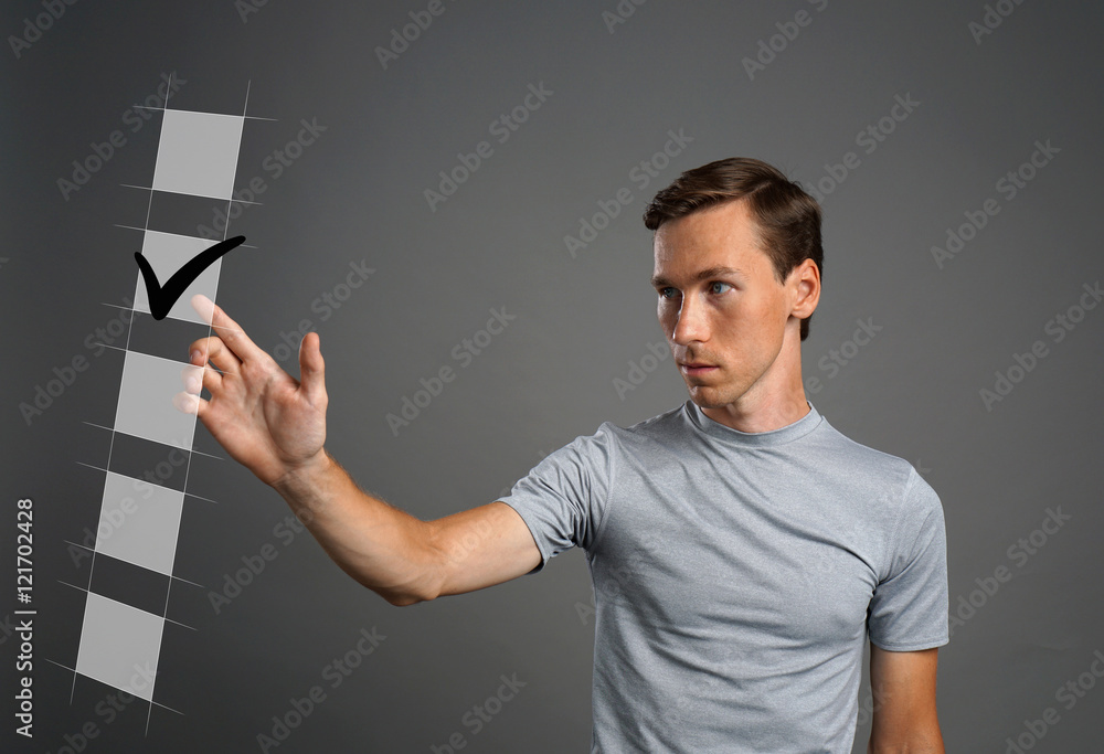 Young man in t-shirt checking on checklist box. Gray background. Stock ...