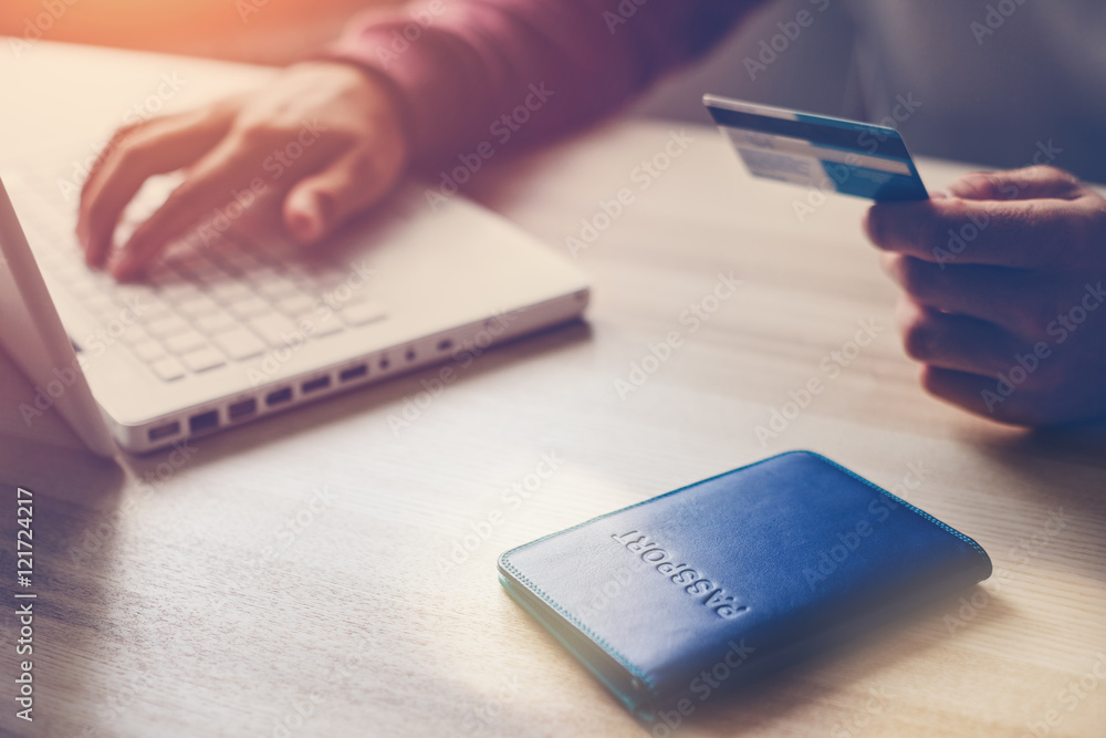 Man holding bank card. Laptop and passport on the table. Web shopping ...