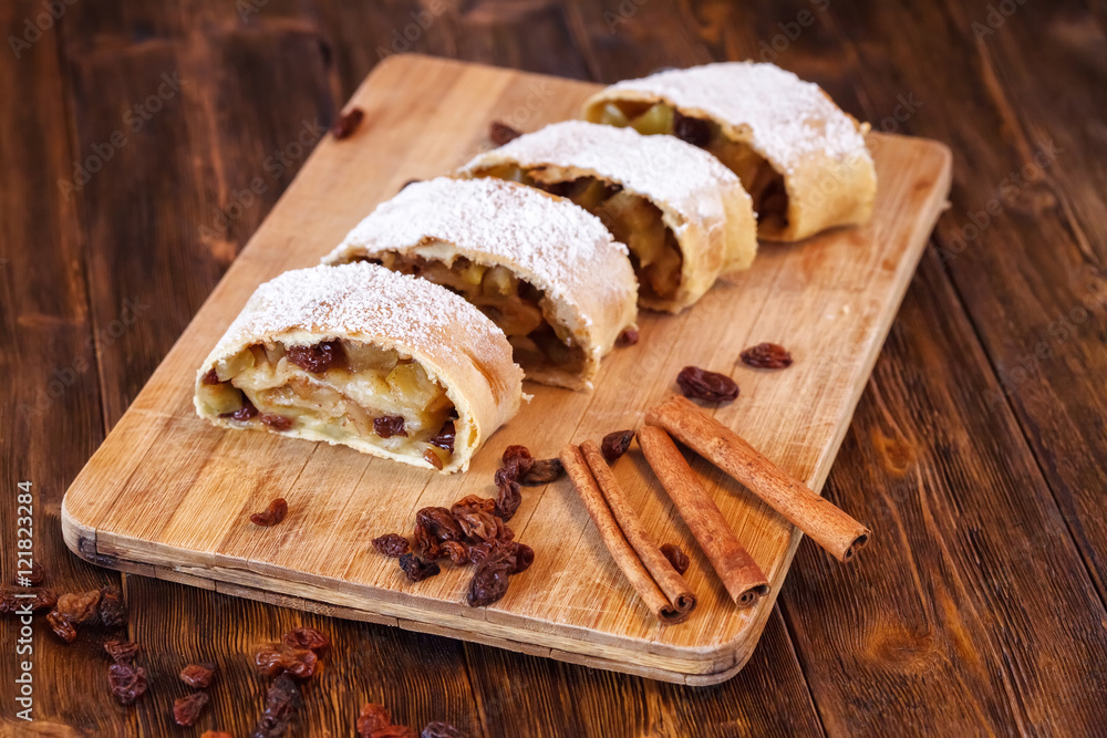 Apple strudel with icing sugar, cinnamon sticks, wooden background ...