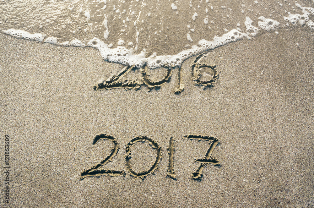 Good bye 2016 hello 2017. 2016 handwritten text letters washed by wave ...