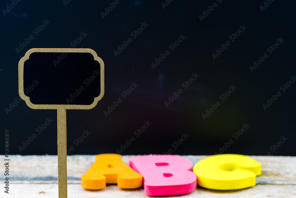 Wooden mini blackboard label over chalkboard background and table with ...