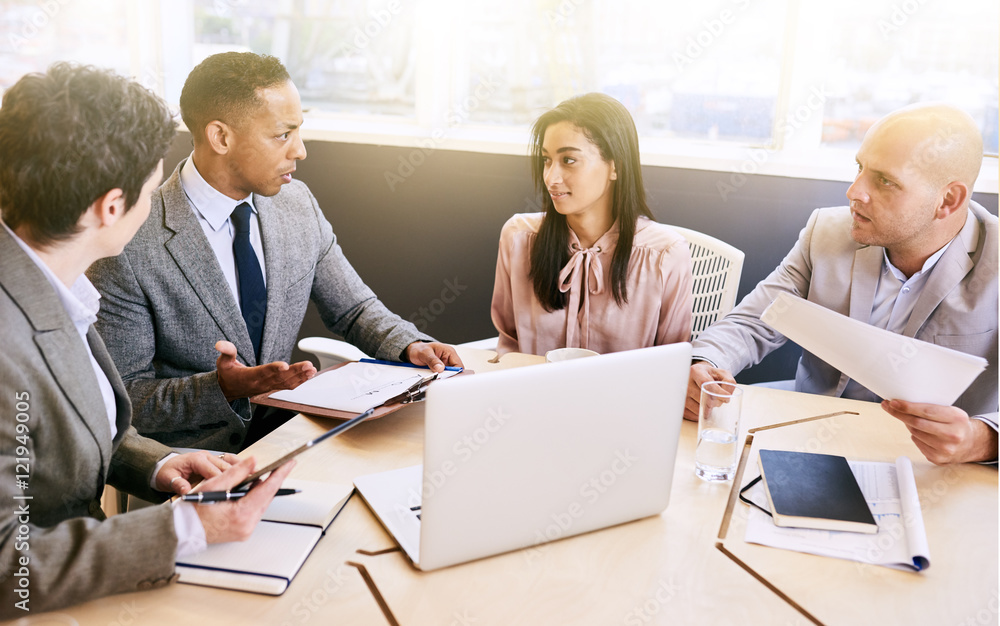 Four business professionals conducting a meeting in a bright modern ...