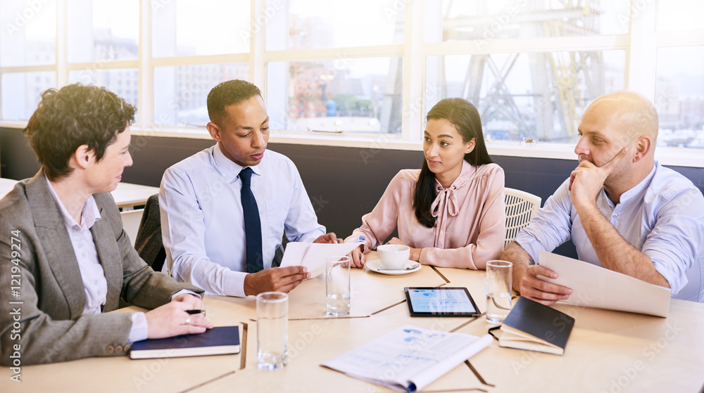 Four business professionals conducting a meeting in a bright modern ...