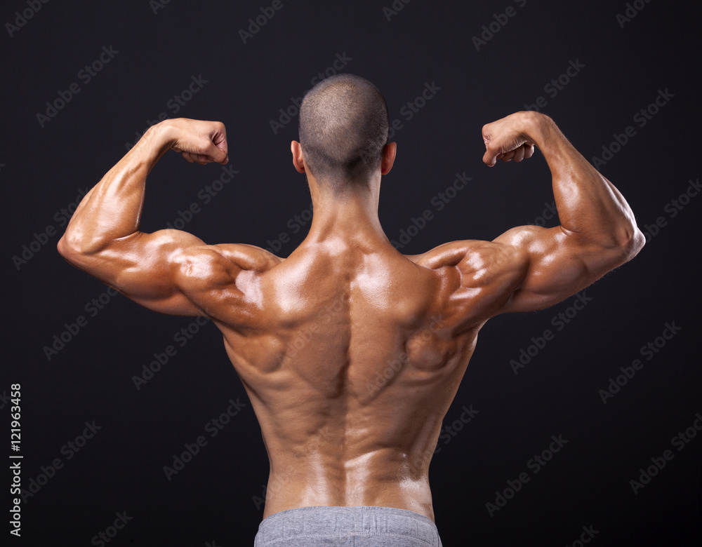 Back view of a male bodybuilder flexing his biceps on black back Stock ...