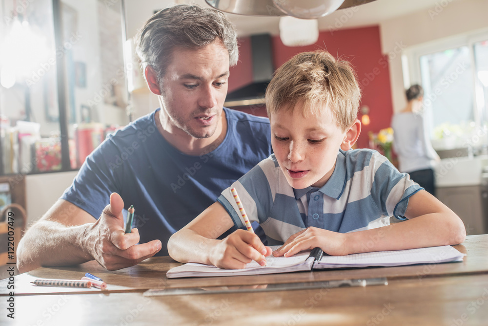Young boy doing his school homework with his father, at home Stock ...