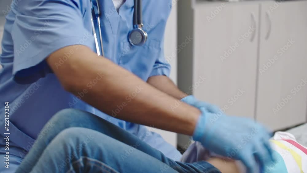 Tilt down of Latin-American doctor pressing on stomach of little ...