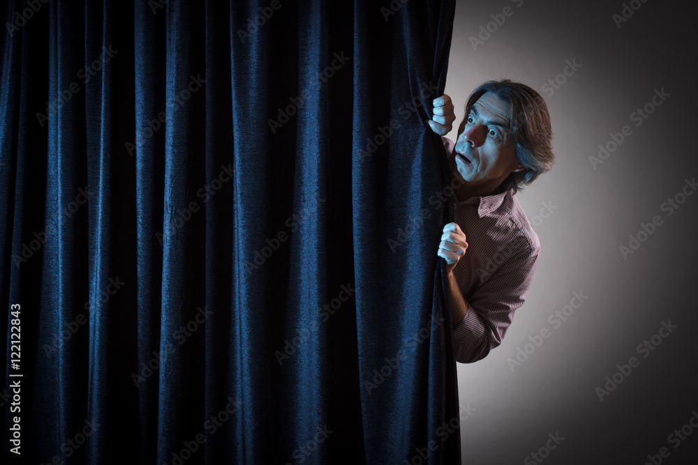 Scared man hiding behind a curtain. Stock Photo | Adobe Stock