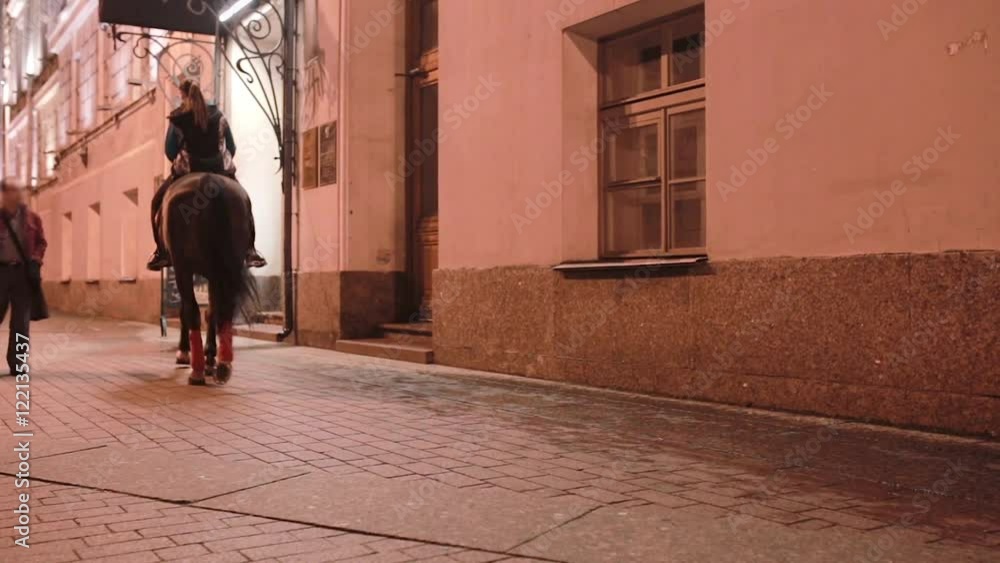 Horse riding in a city. Jockey on a horse in the street at night moving ...