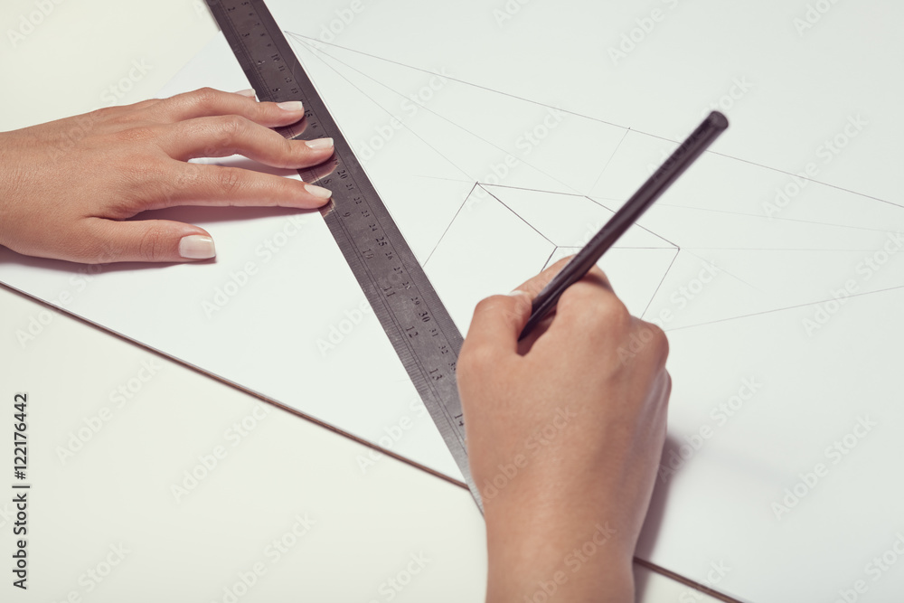female hand drawing a cube with pen and ruler in two point perspective ...
