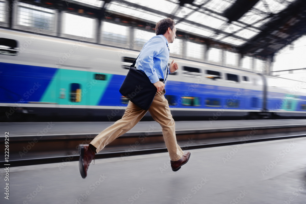 Rushed businessman running through railway station to catch last train ...