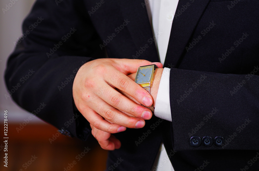 Closeup man's arm wearing suit, adjusting silver wrist watch using ...