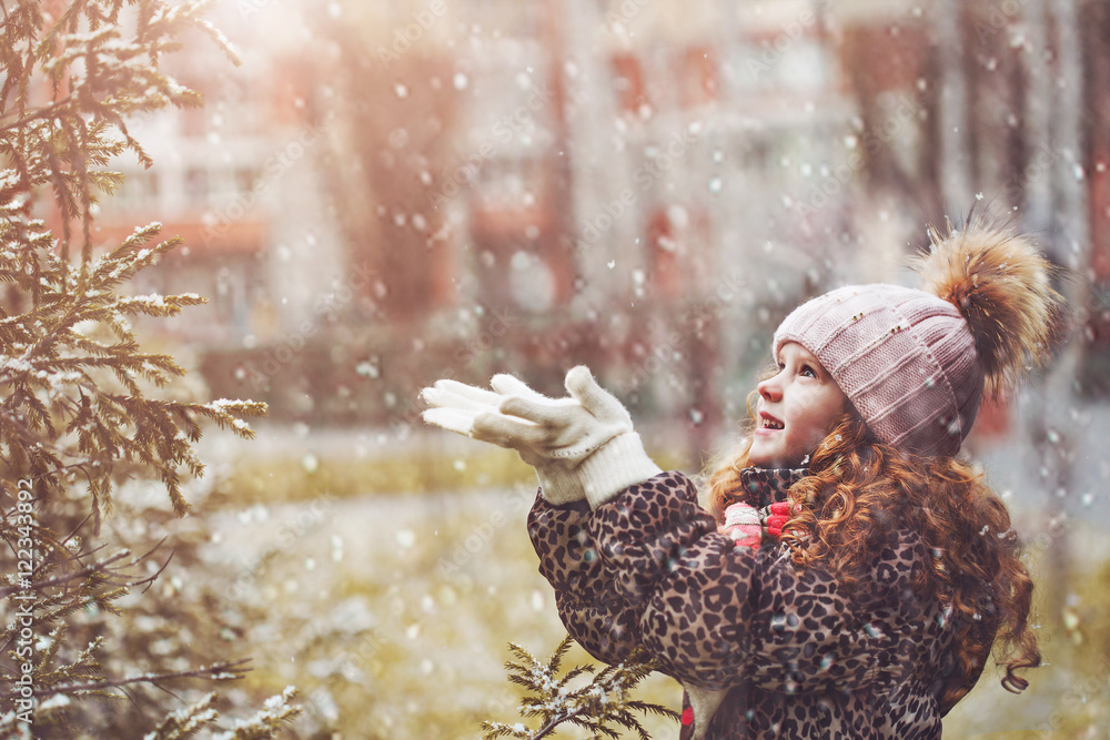 Little girl catches falling snowflakes. Stock-Foto | Adobe Stock