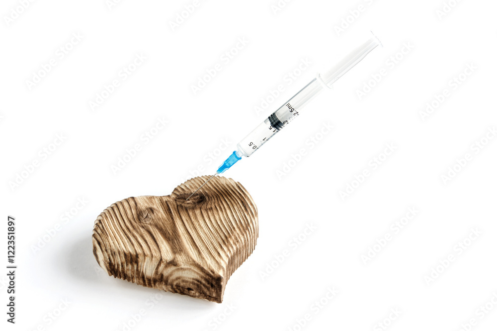 Wooden texture heart with a syringe stuck a needle prick. Isolated on ...