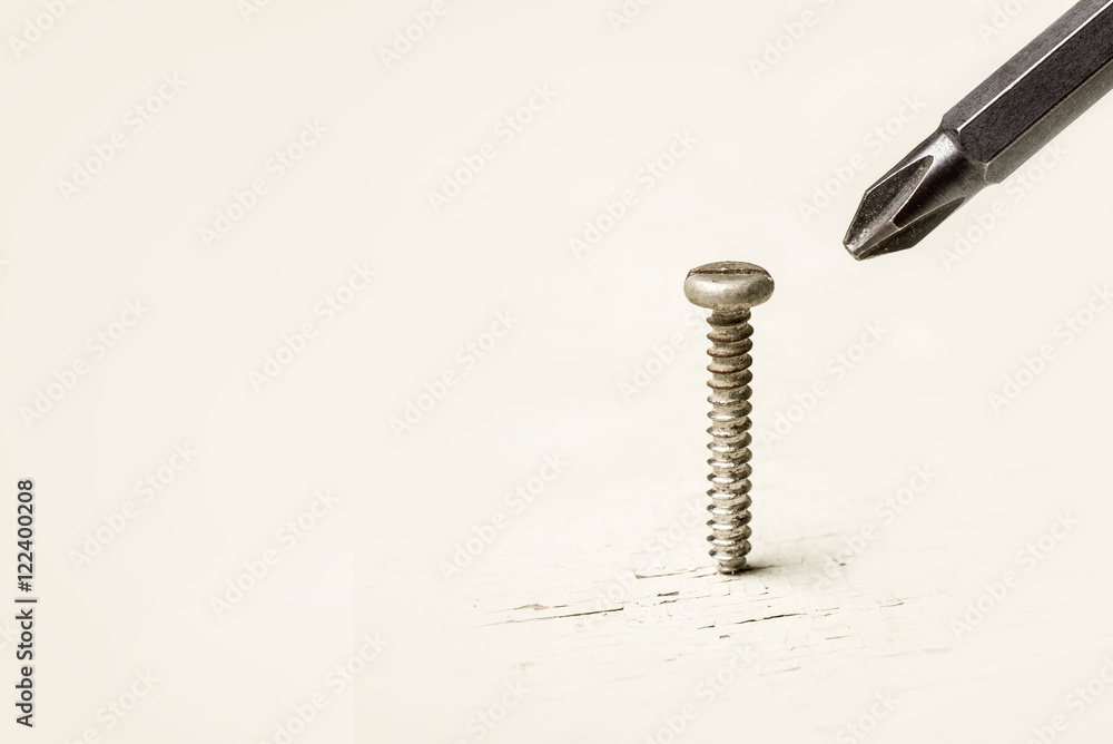 screwdriver and screw on old white wood with copy space, wrong tool for ...