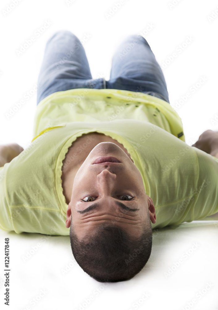 Handsome young man laying on the floor, belly up, looking at camera ...