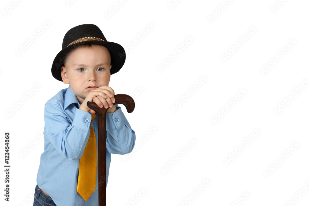 Little boy in black hat and yellow tie stands bored leaning on cane ...