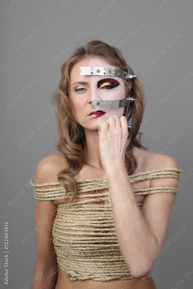 Pretty young woman with long wavy hair, with pale angry makeup and iron ...