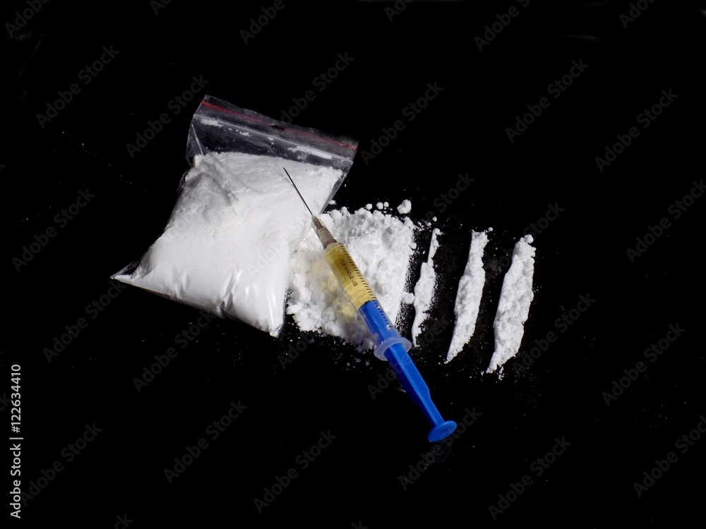 Injection syringe on cocaine drug powder pile and lines and cocaine bag ...