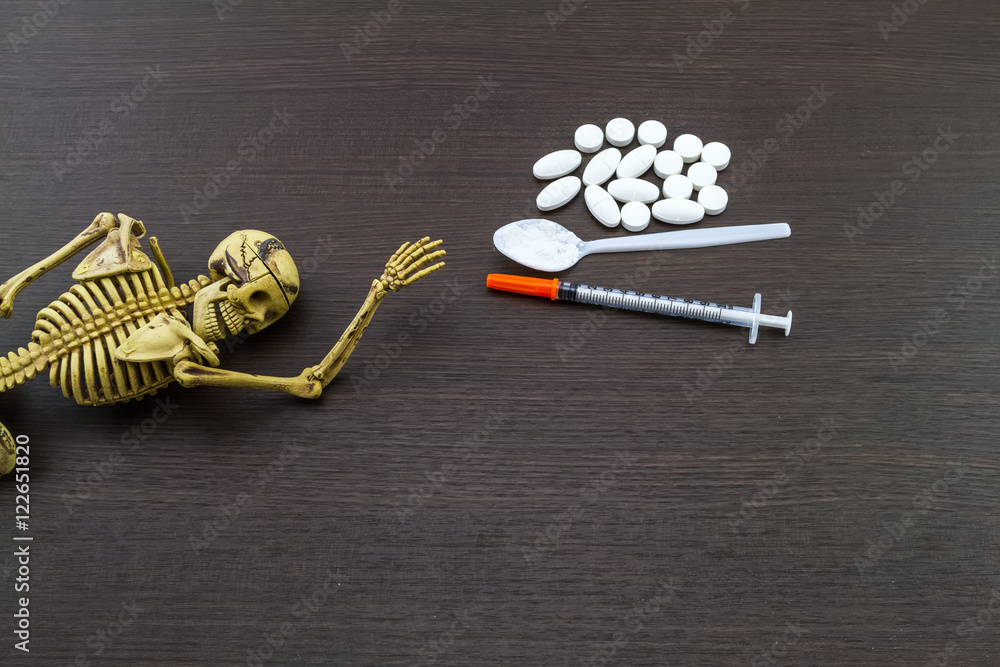 Skull and drugs with insulin syringe. Next to them are a spoon with ...