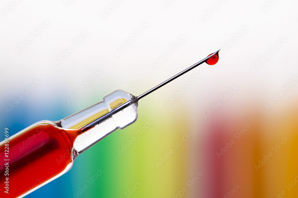 Macro of a single drop of blood hanging at the end of a syringe needle ...