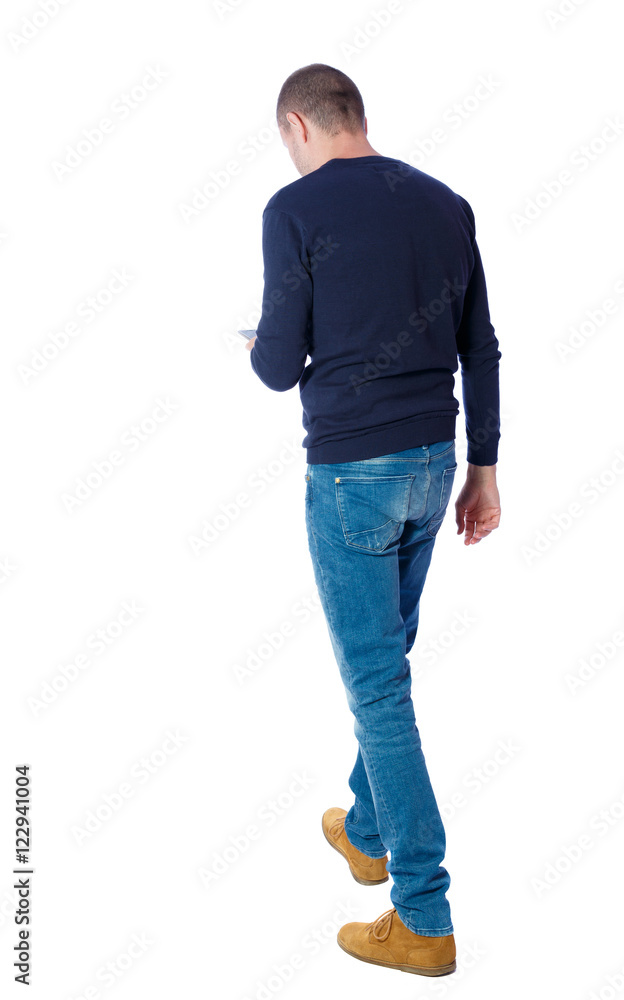back view of a man walking with a mobile phone. back view of man in ...