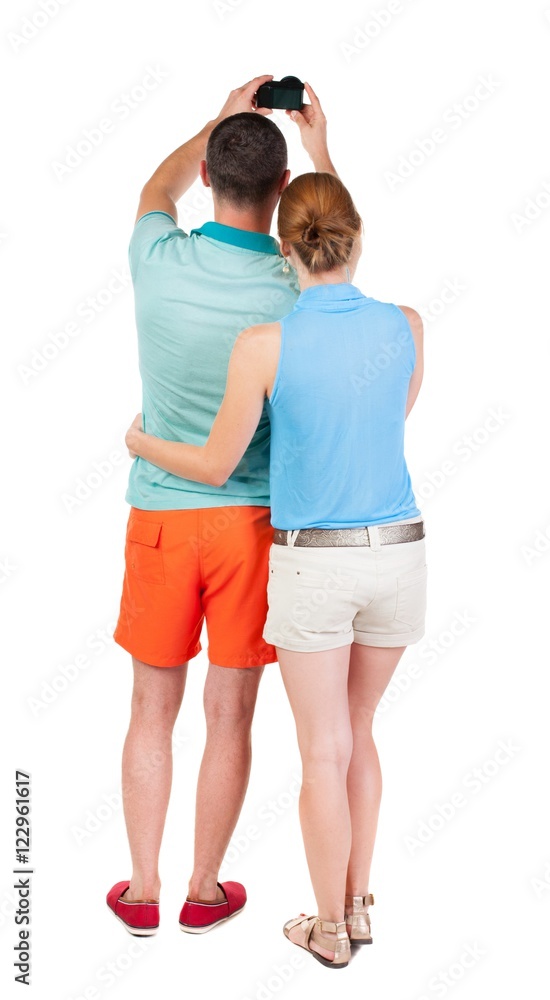 Back view of couple photographing. Tourists take pictures of the family ...