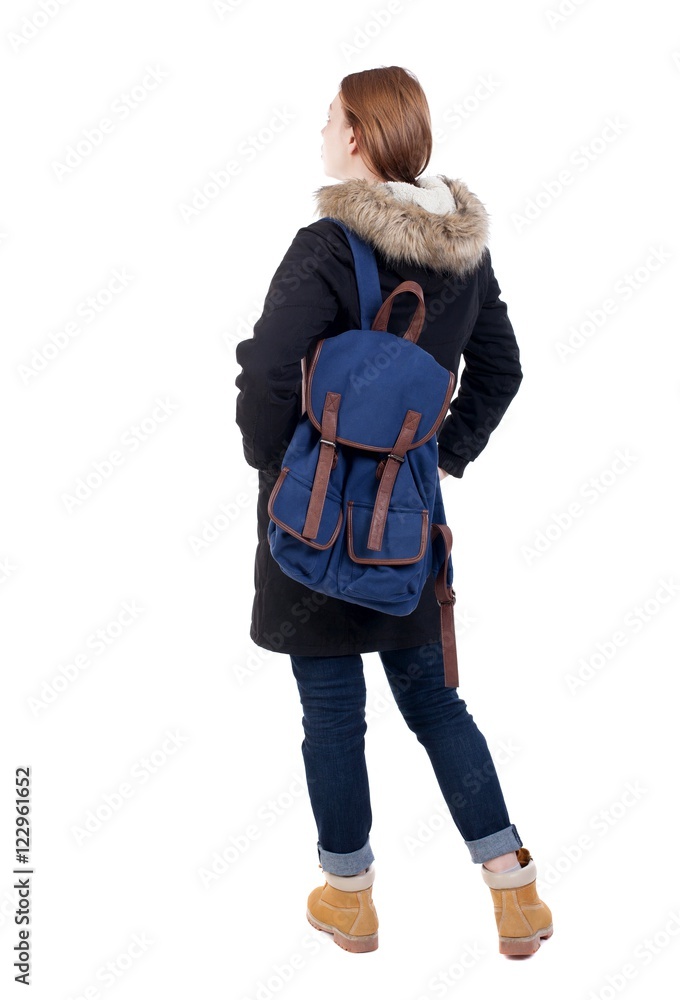Back view woman in winter jacket with a backpack looking up. Standing ...
