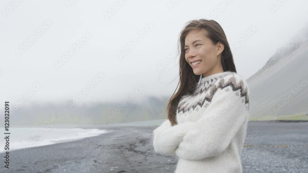 Beautiful woman walking on black sand beach on Iceland wearing ...