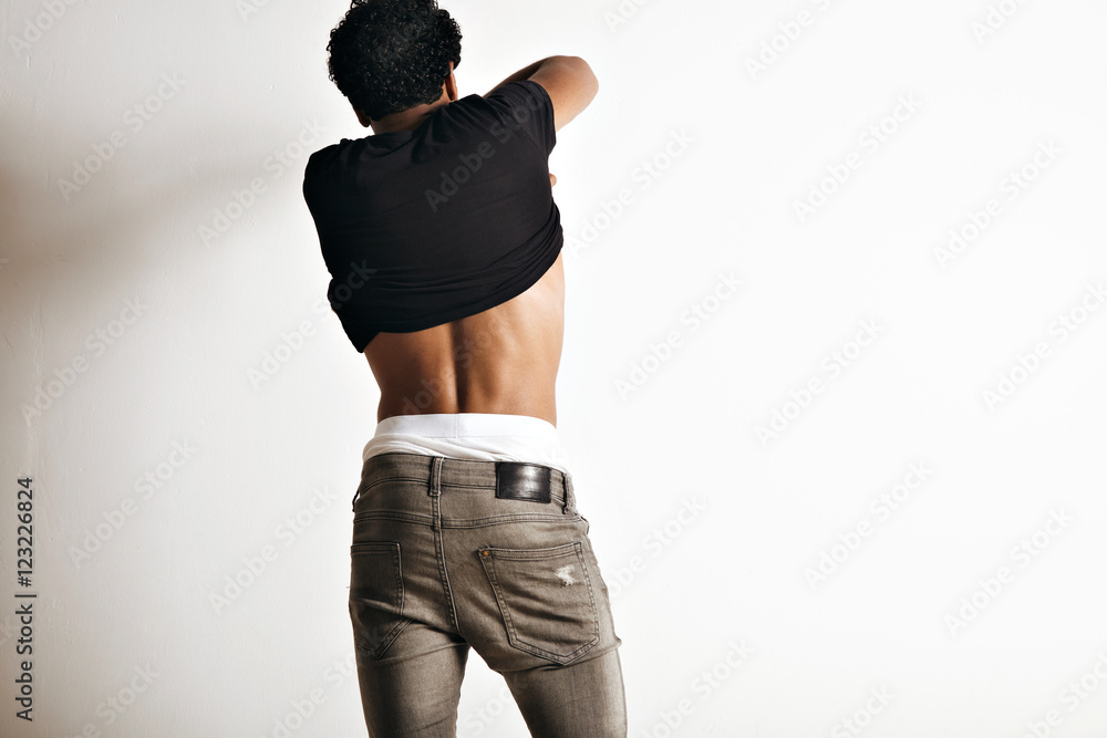 Back shot of a muscular young model taking off his black unlabeled ...